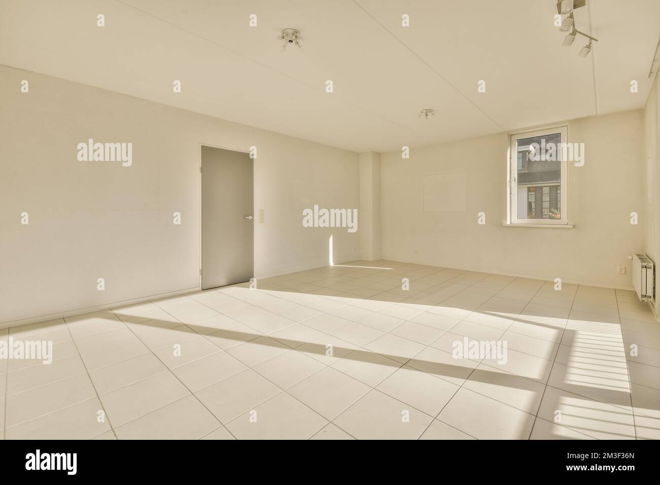 an empty room with white tiles on the floor and light coming in through ...