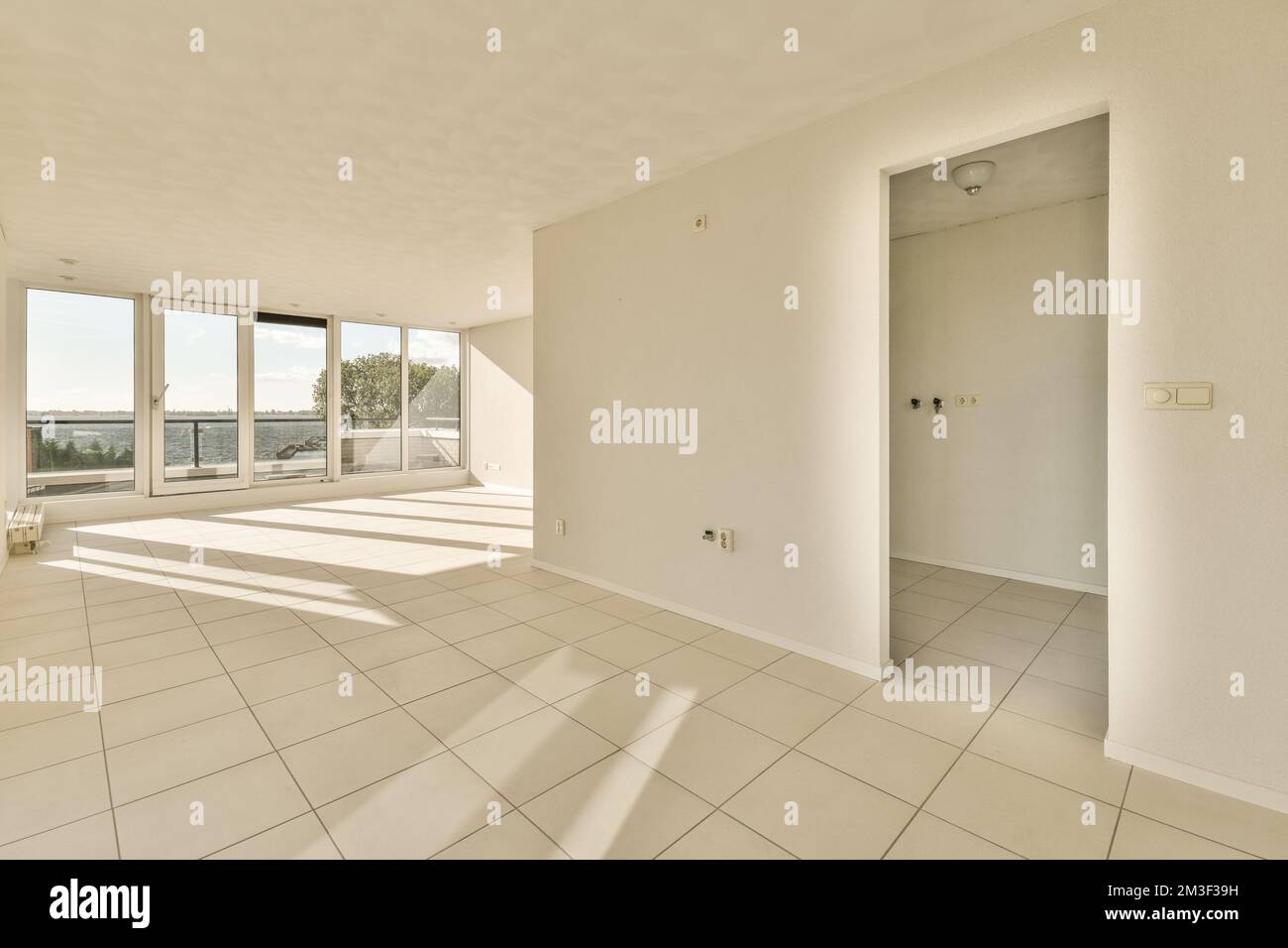 an empty room with white tile flooring and large windows looking out ...