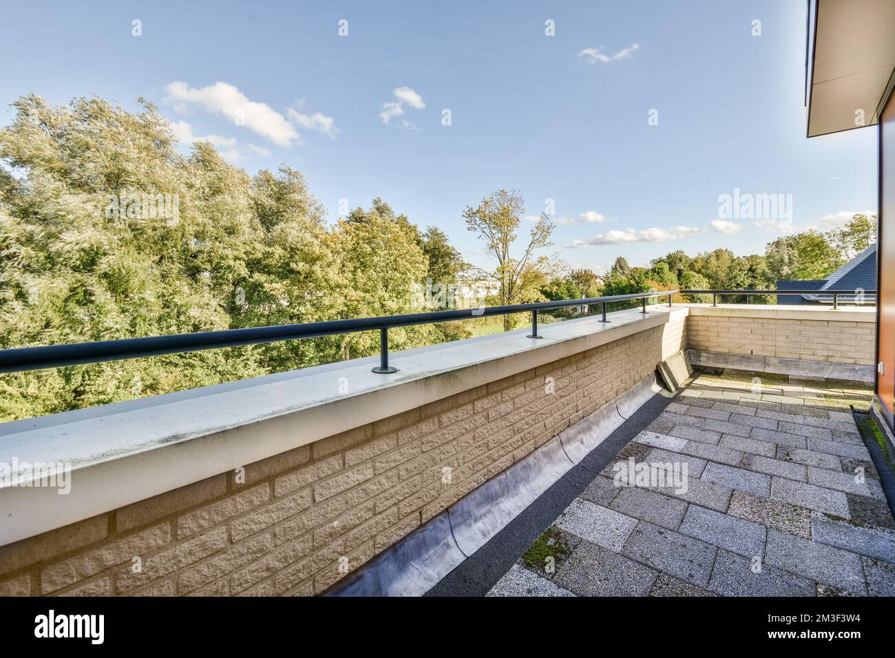 a balcony with trees and blue sky in the background, taken from inside ...