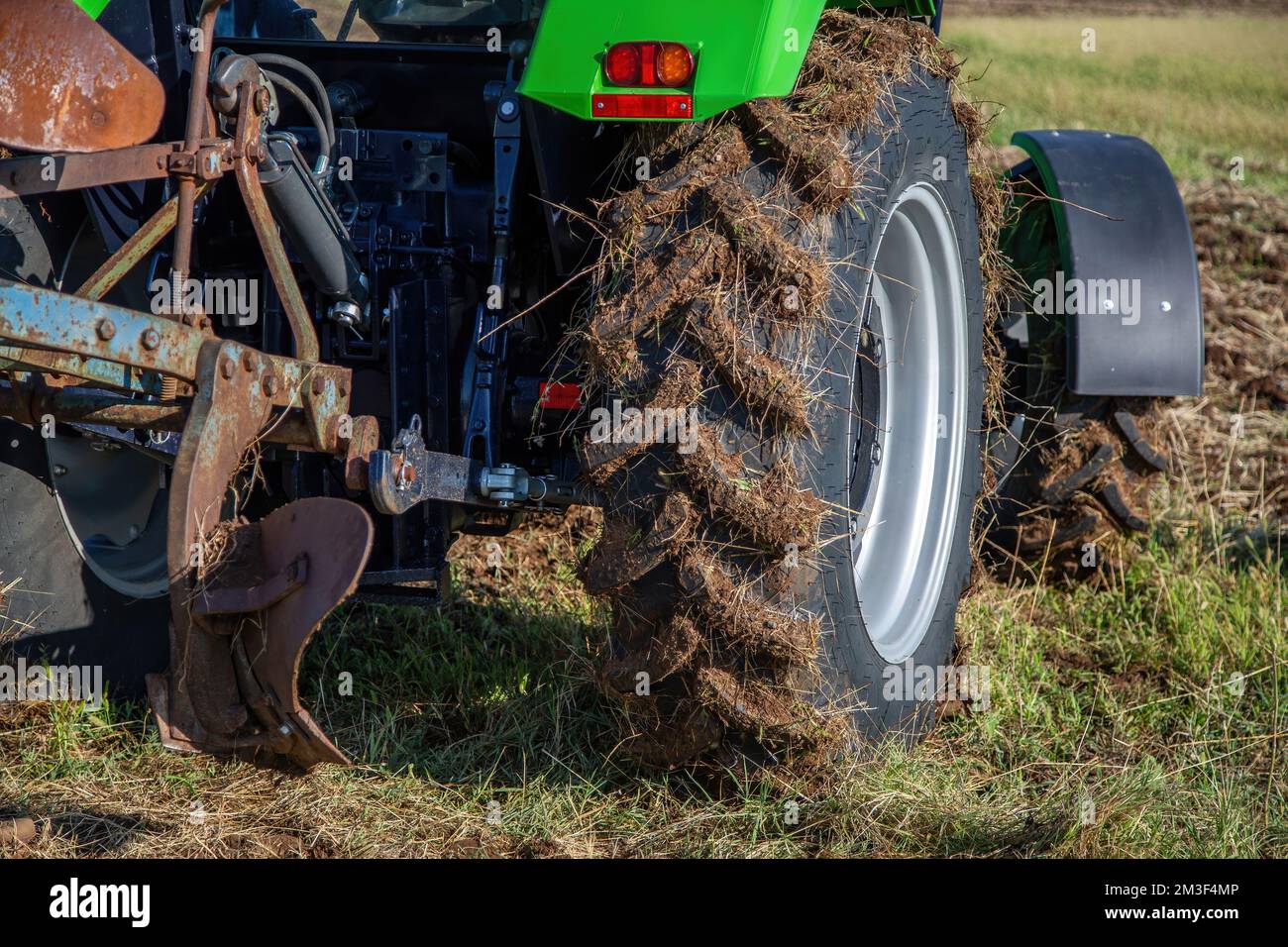 Agriculture concept. Tractor with plough, close up view of wheel ...