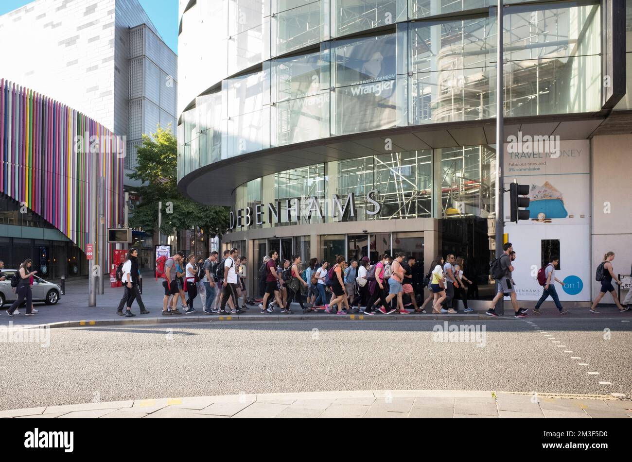 Shoppers tourists and visitors crossing the road outside Debenhams and ...