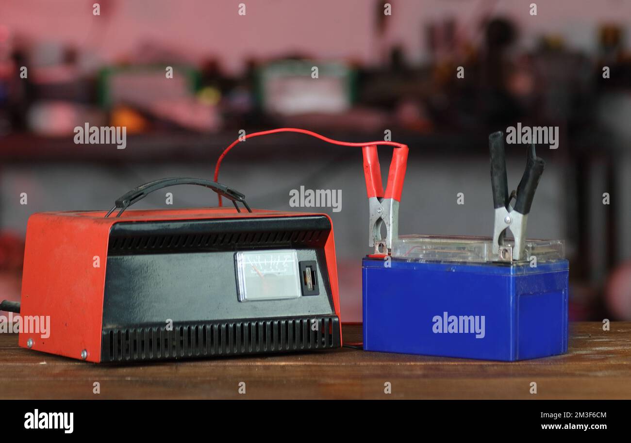 charging a small battery from the scooter in the garage Stock Photo - Alamy