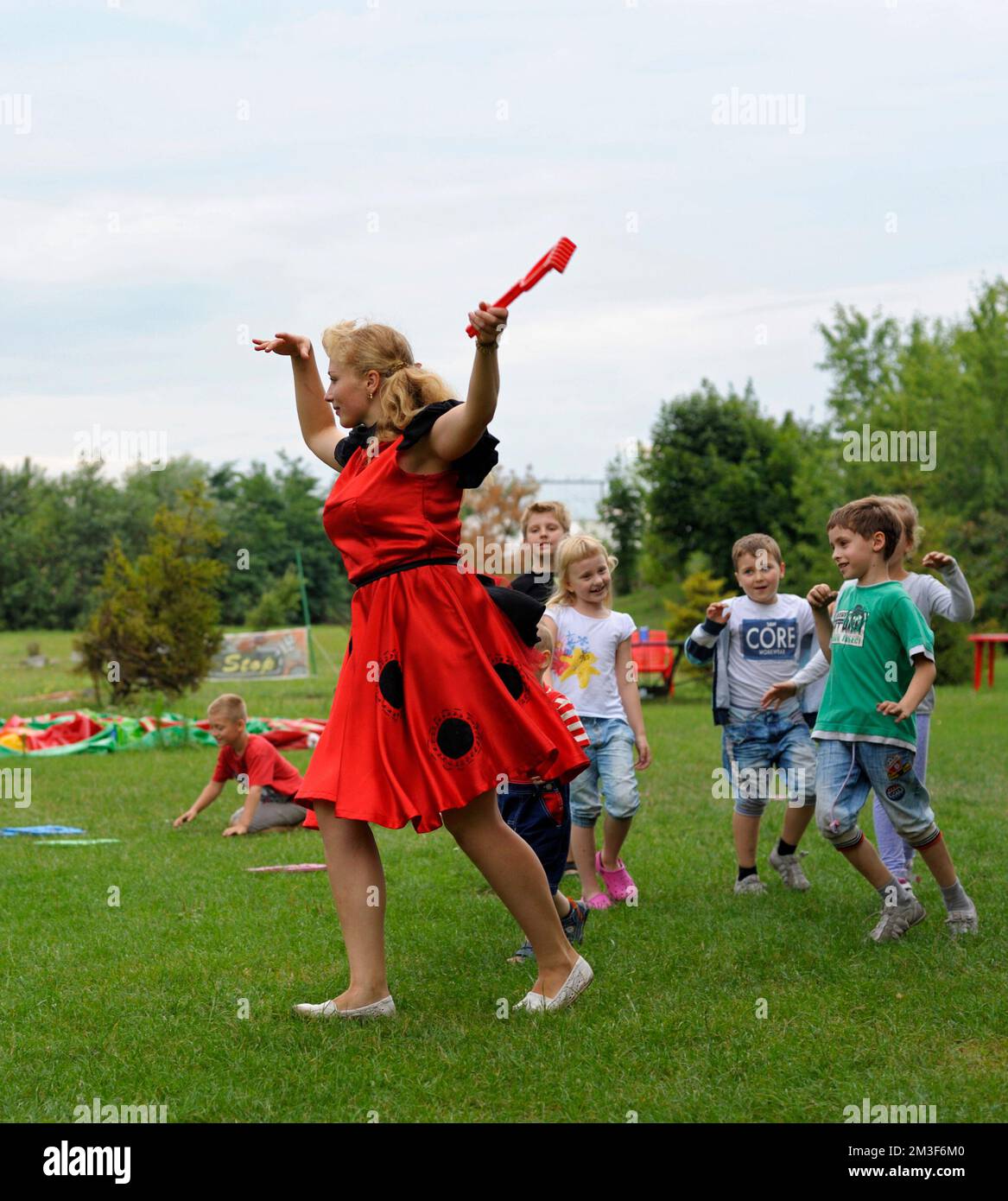 Young woman nanny playing dancing with children on a playground in a ...