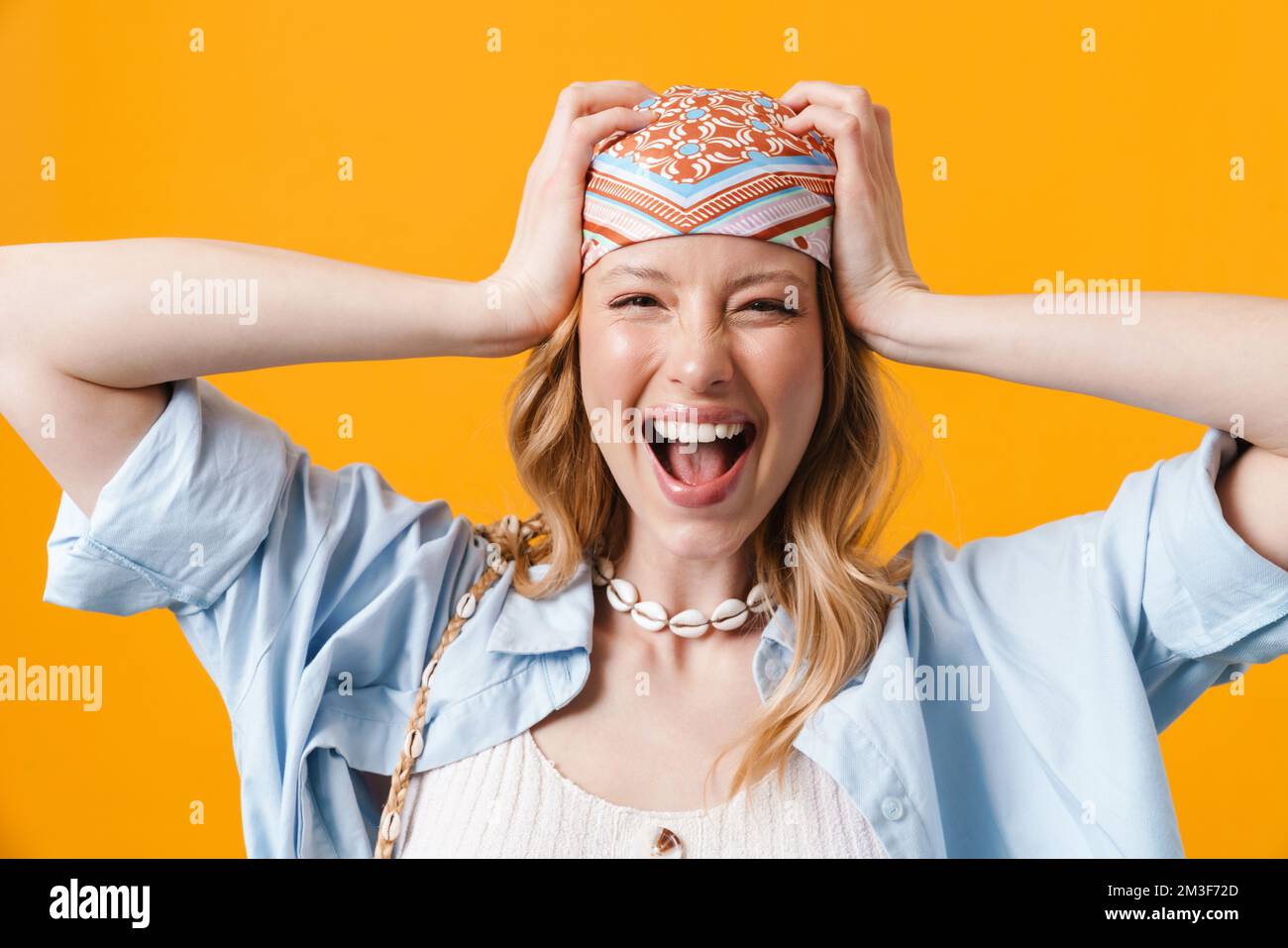 Young blonde woman screaming while holding her head isolated over ...