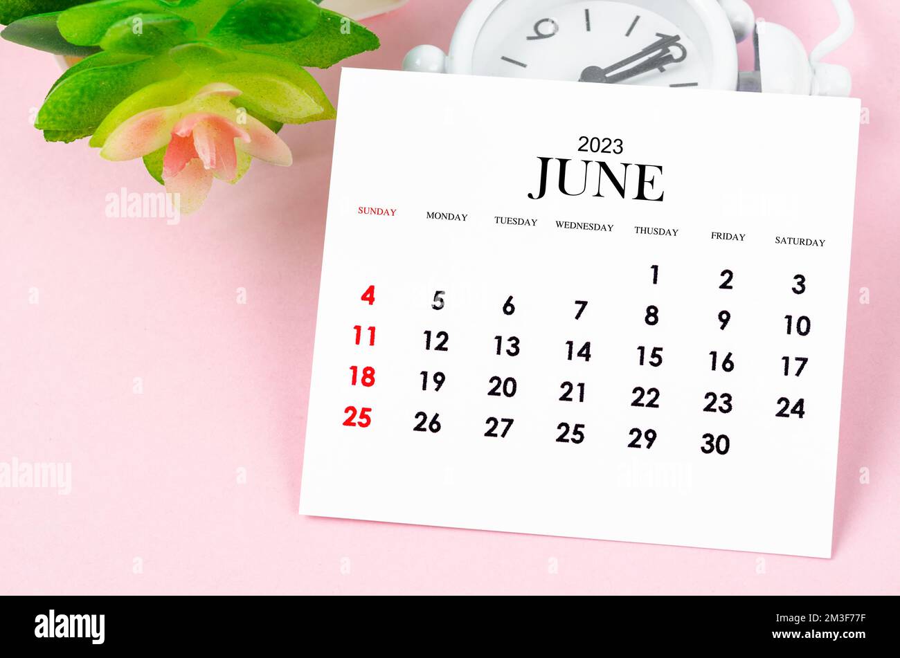 June 2023 Monthly calendar for 2023 year with vintage alarm clock on pink colour background ...