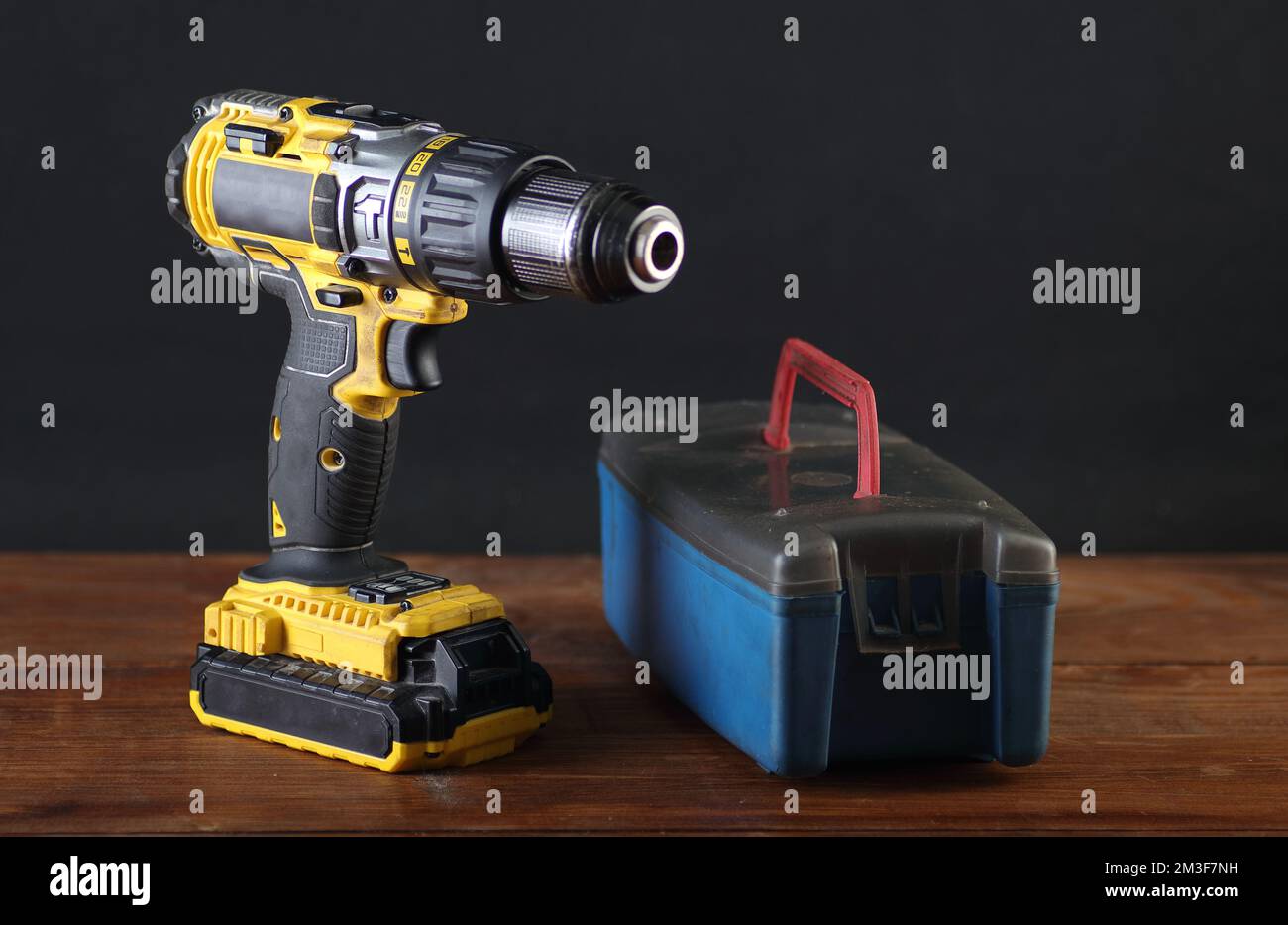 yellow screwdriver with a box of drill bits on the table and gray ...