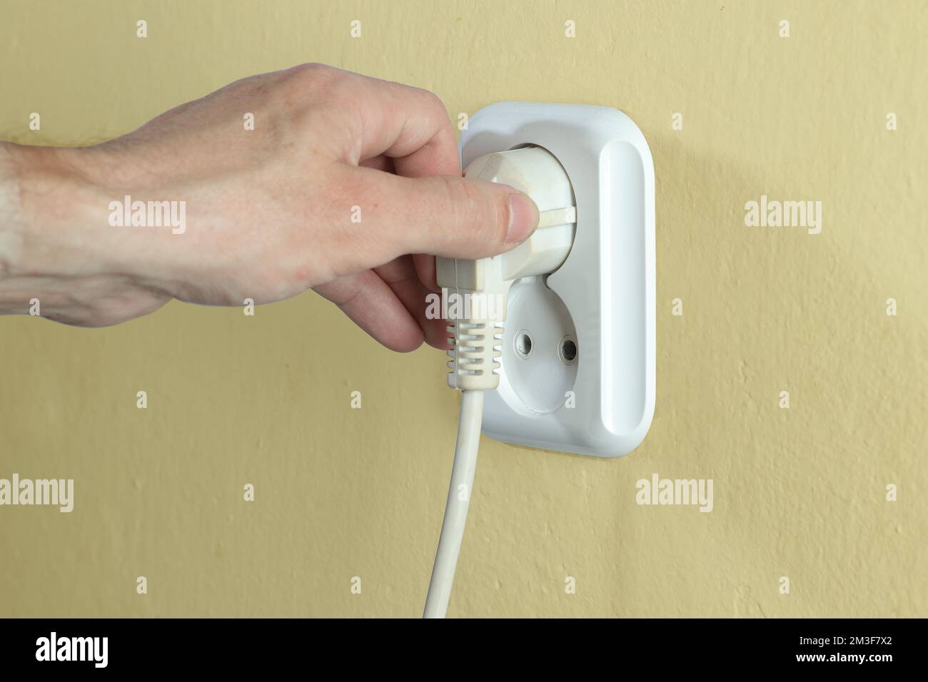 inserting the plug into the socket against the background of the wall ...
