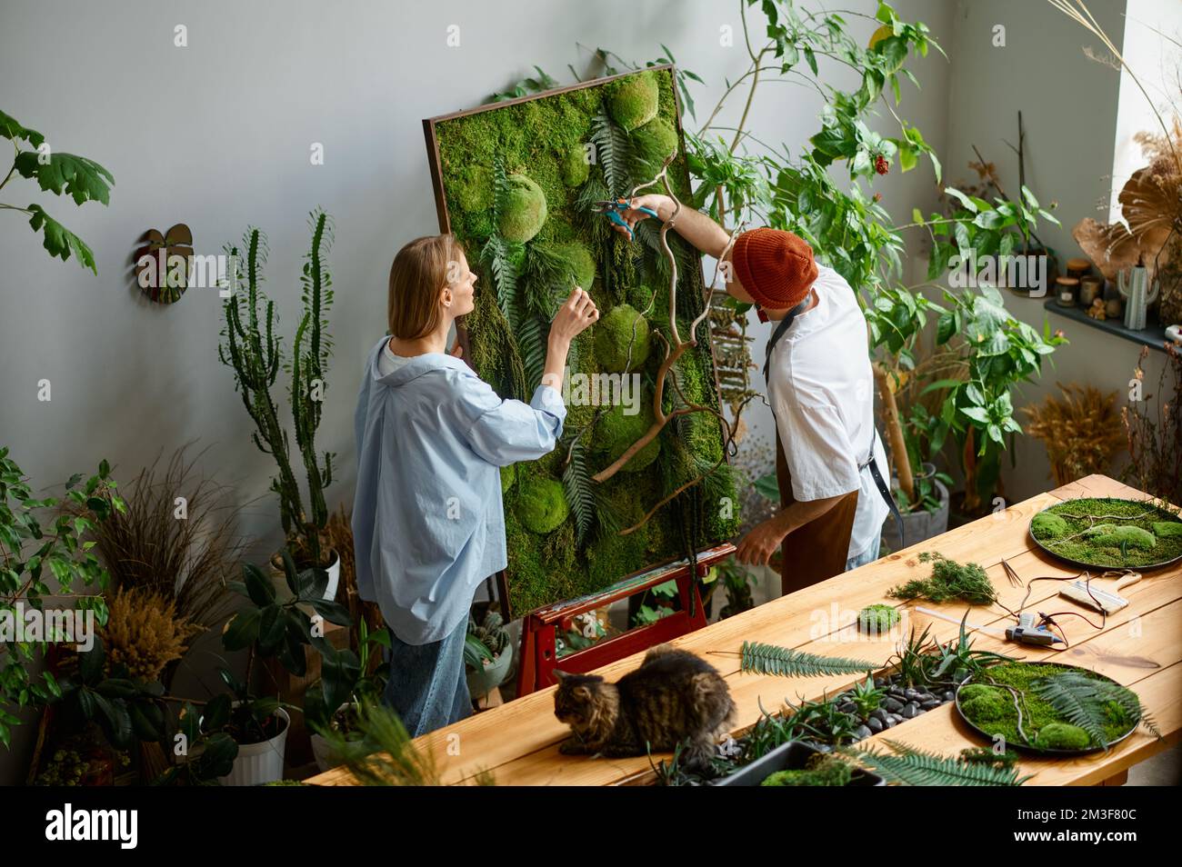 Florist and decorator making handicraft artwork from plants overhead ...