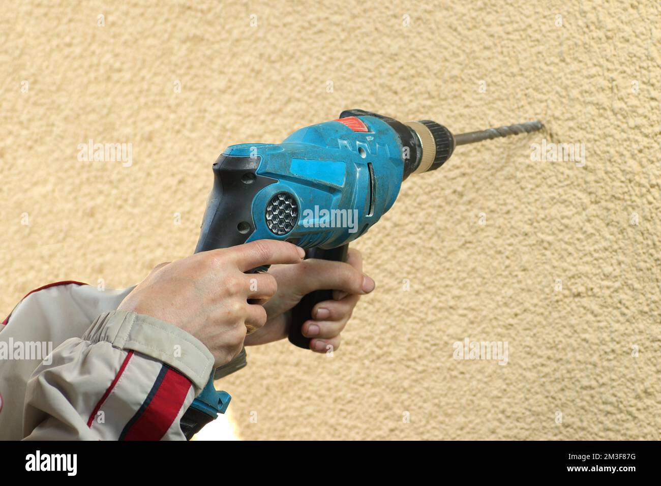 drilling in the wall with a blue drill by a young man Stock Photo - Alamy