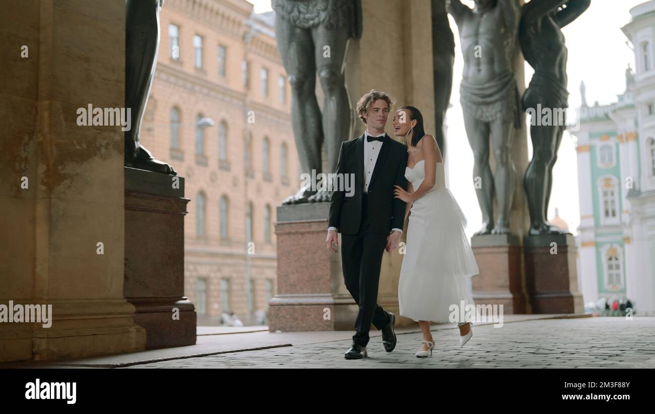 Beautiful newlyweds walking along European street. Action. Happy ...