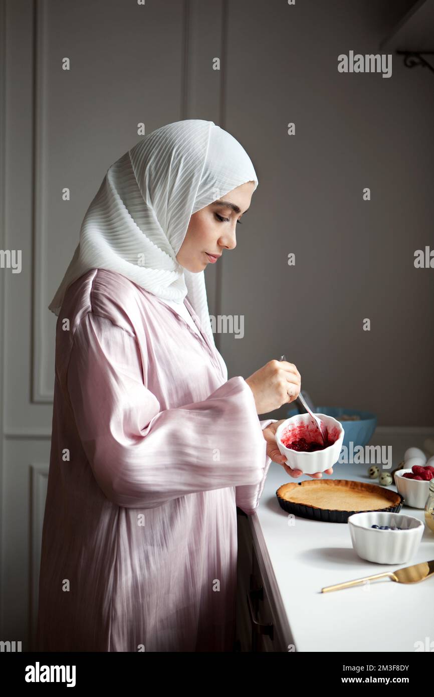 Side view portrait Muslim woman cooks dessert cake at kitchen, arabian ...