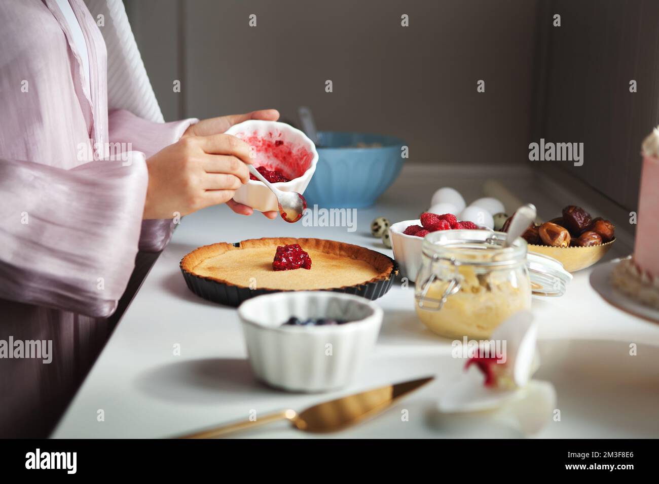 Close up of woman hands preparing cake with raspberries and dates ...