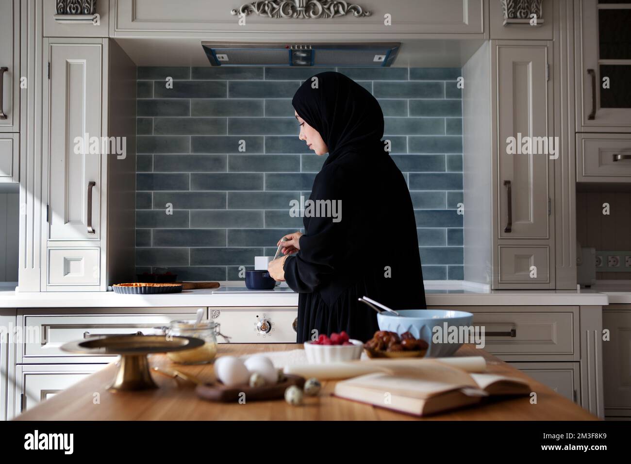 Arabian woman cooking in home kitchen, wears black abaya and hijab ...