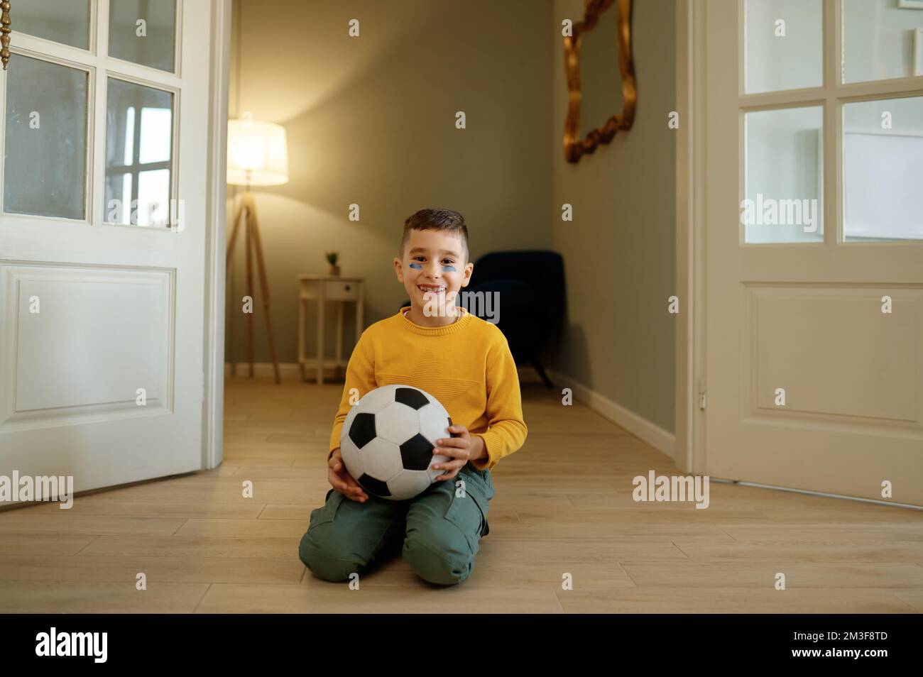 Happy boy football fan posing for camera with soccer ball at home Stock ...