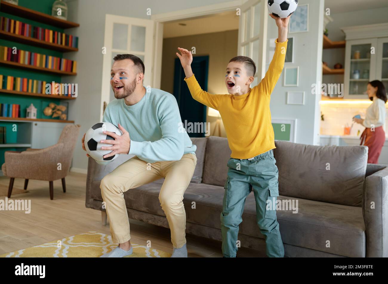 Excited father and son cheering and watching football match at home ...