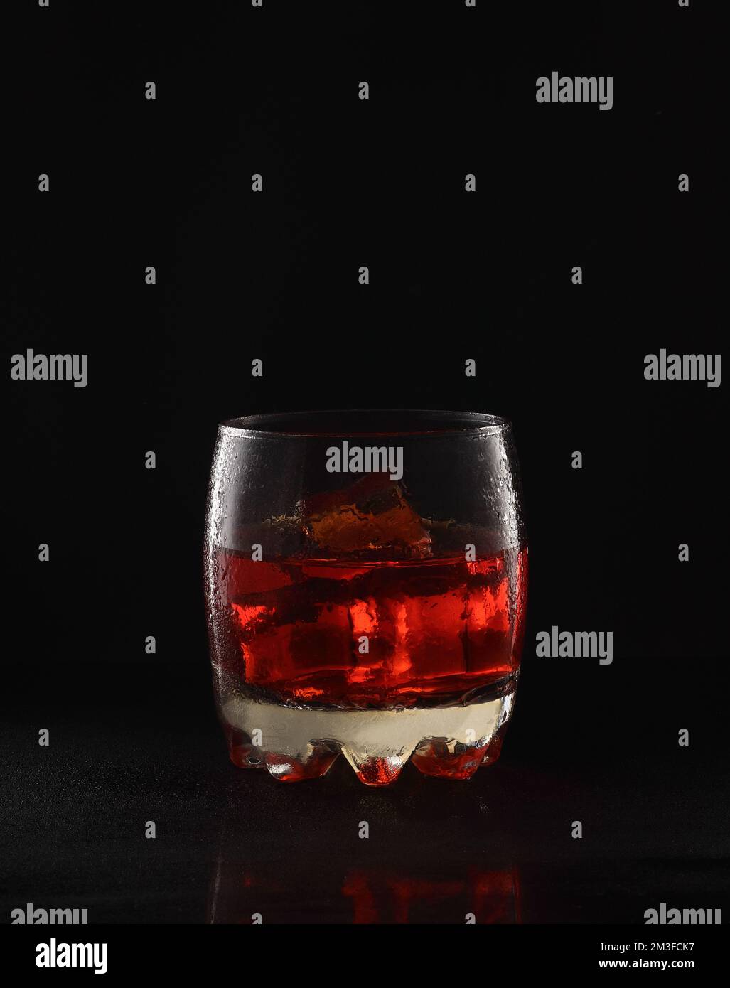 glass with red alcohol on a black background Stock Photo - Alamy