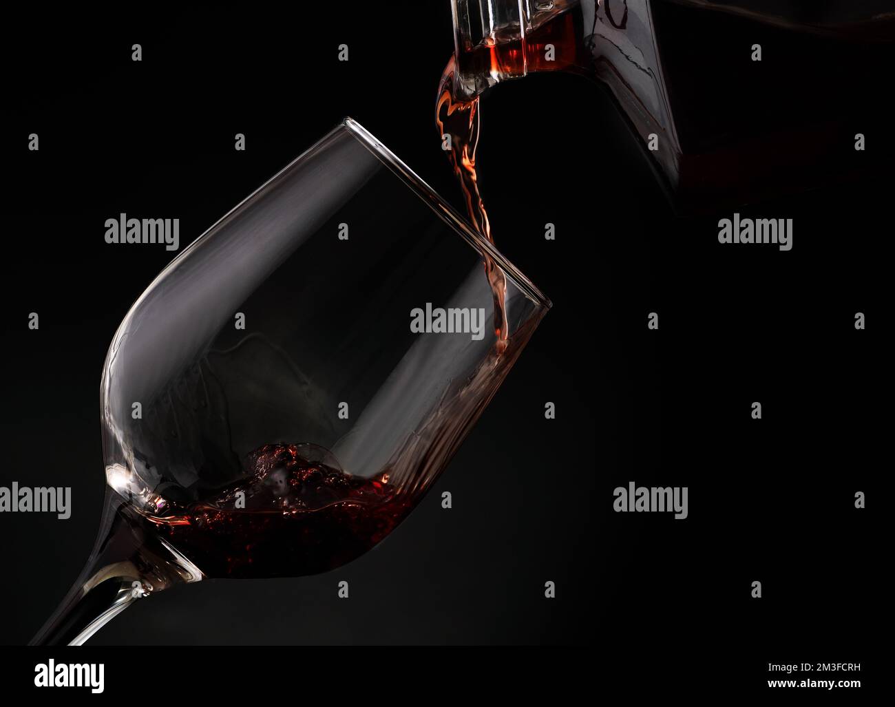 pouring alcohol into a glass on a black background Stock Photo - Alamy