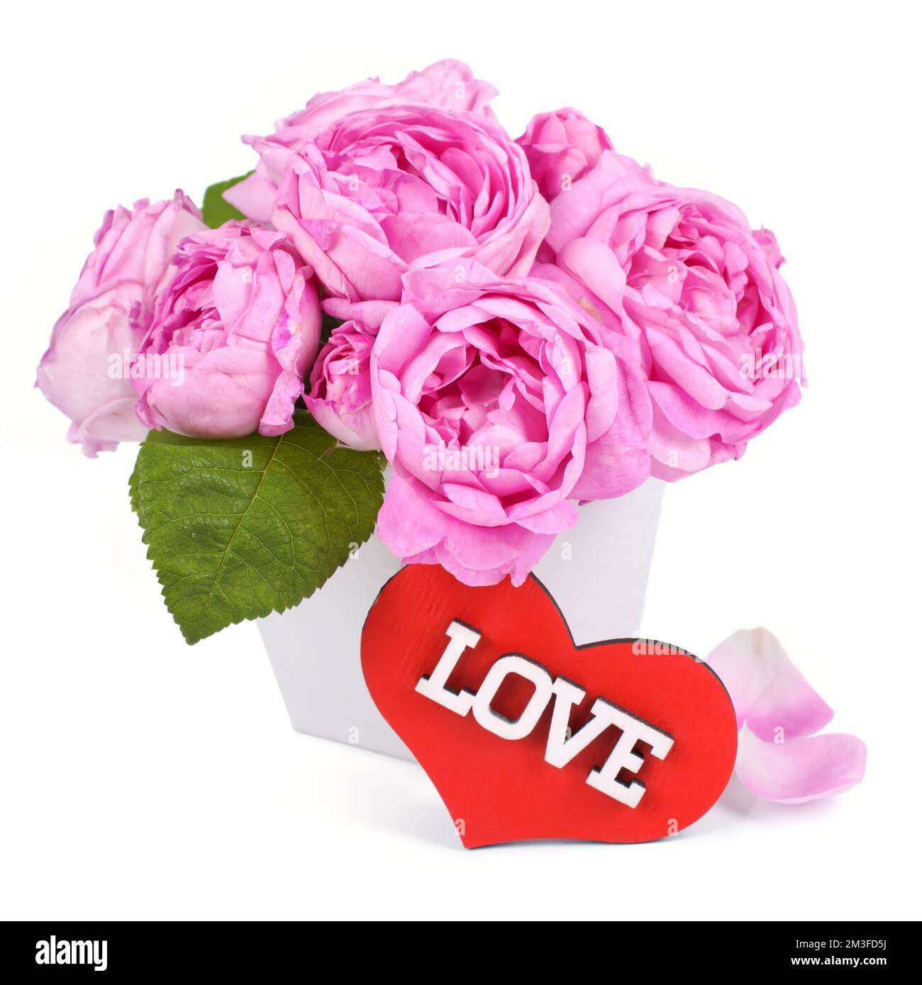 Pink roses and petals on wooden desk and red wooden heart shape with ...