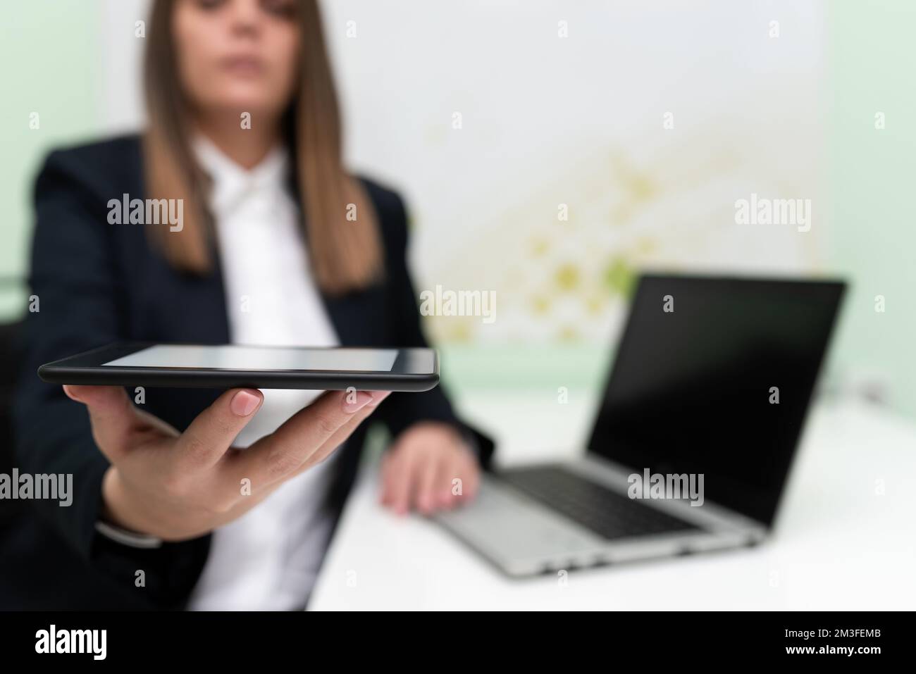 Businesswoman Holding Tablet With One Hand And Having Lap Top On Desk ...