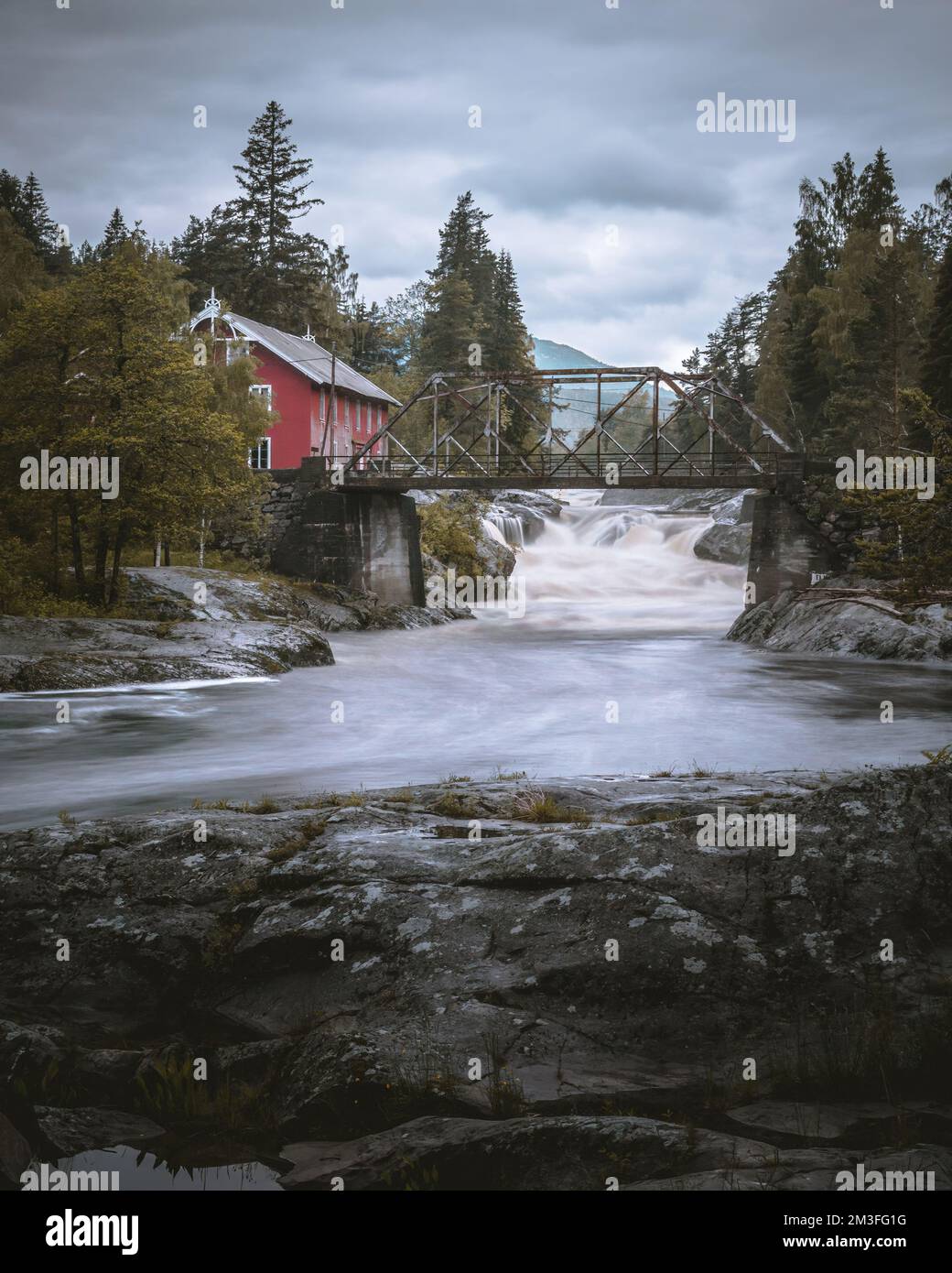 A cottage and an old metal bridge over the wild Heddola river, Norway ...