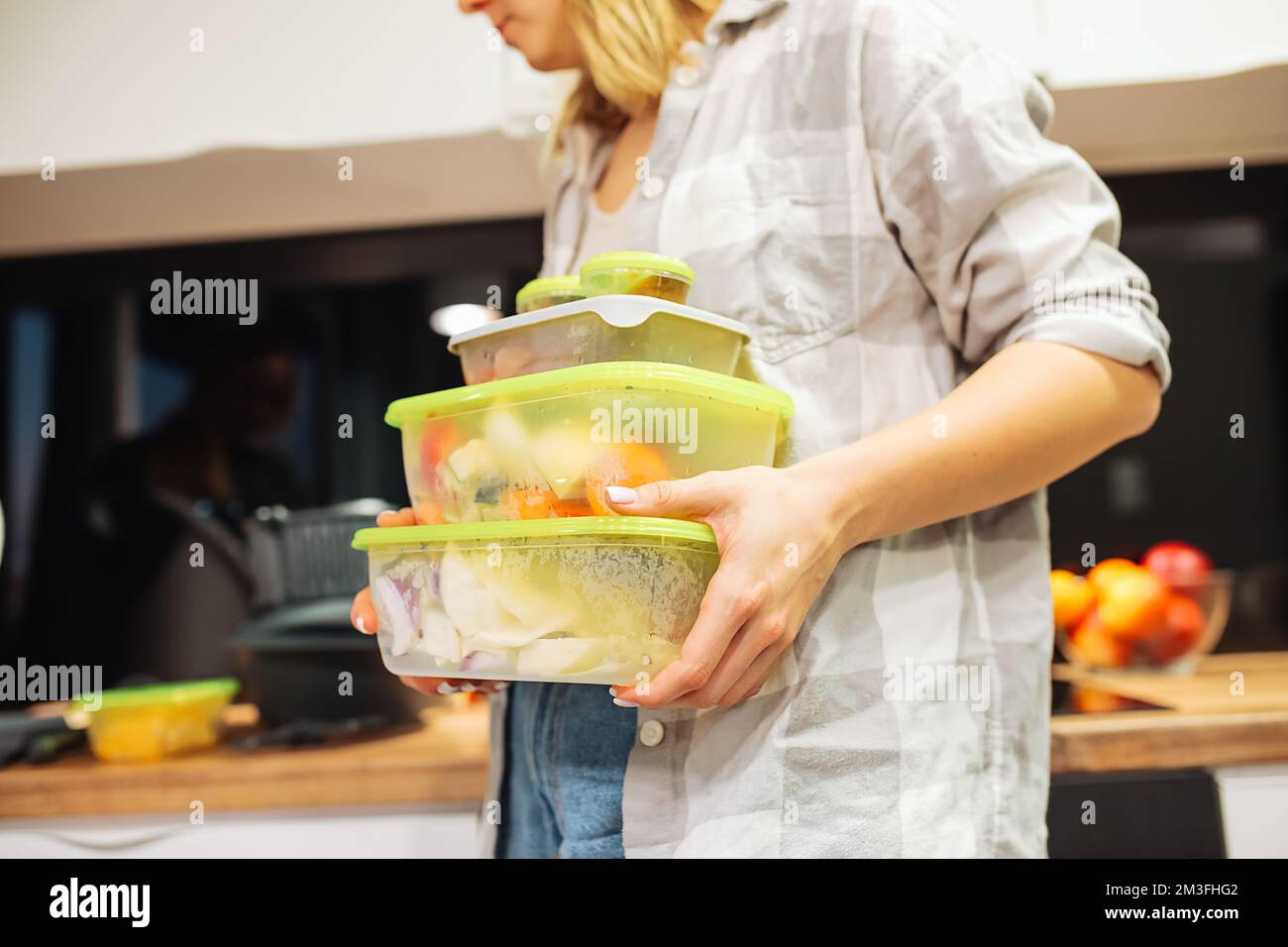 Unrecognizable women prepare food in stack of plastic containers in ...