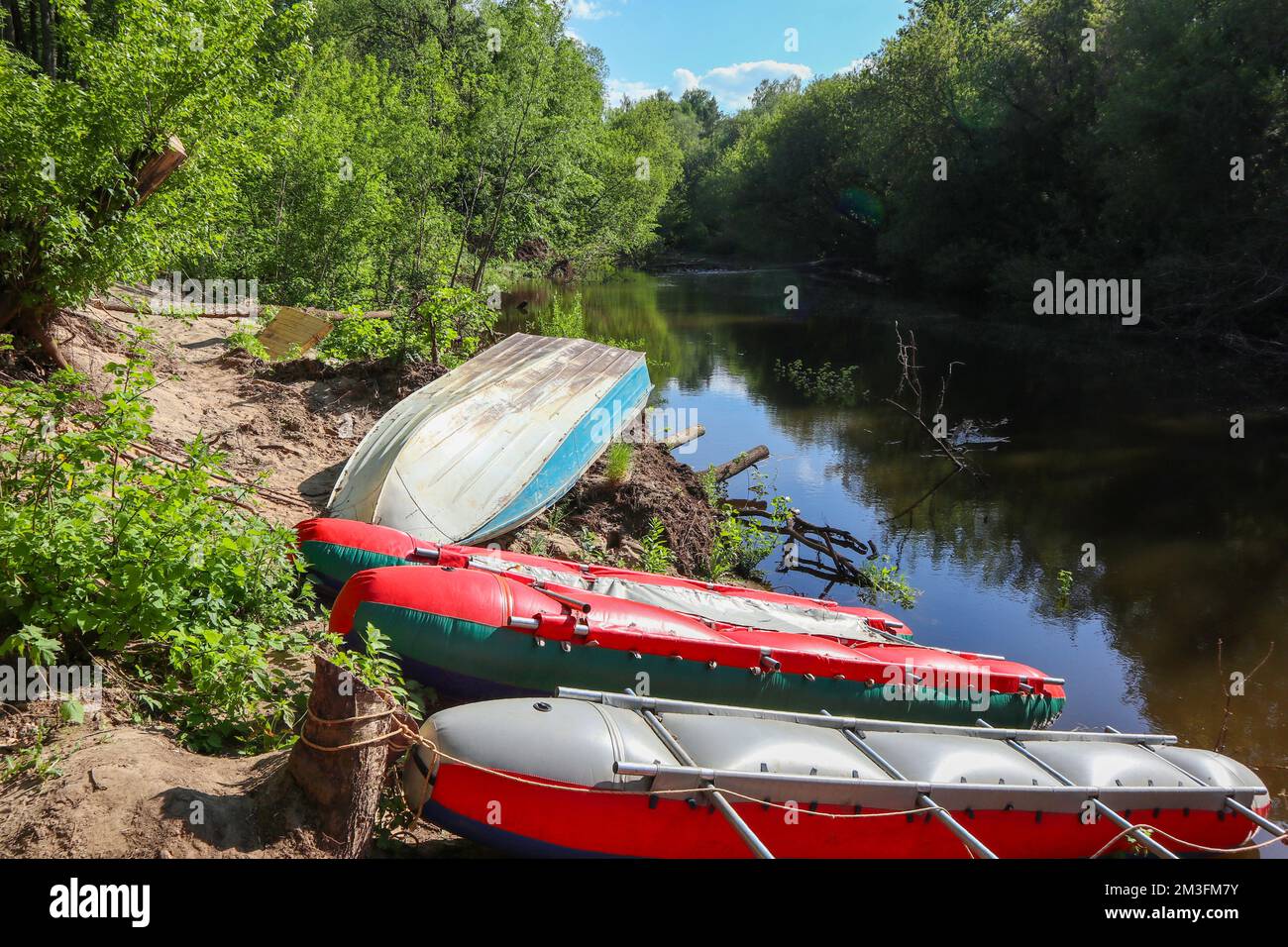 an overturned boat and inflated catamarans on the river bank Stock ...
