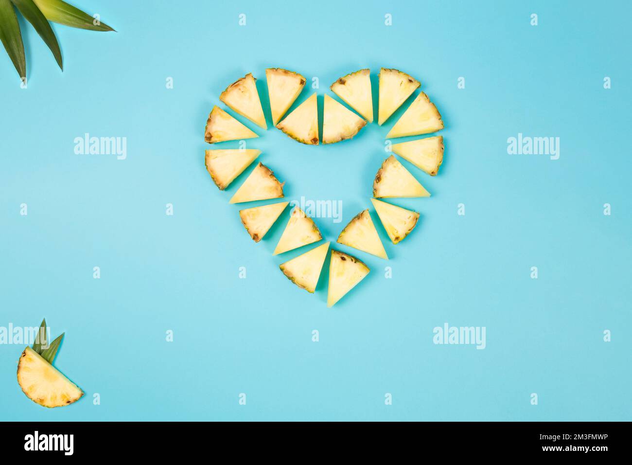 pineapple slices forming a heart on the ground on a blue background ...