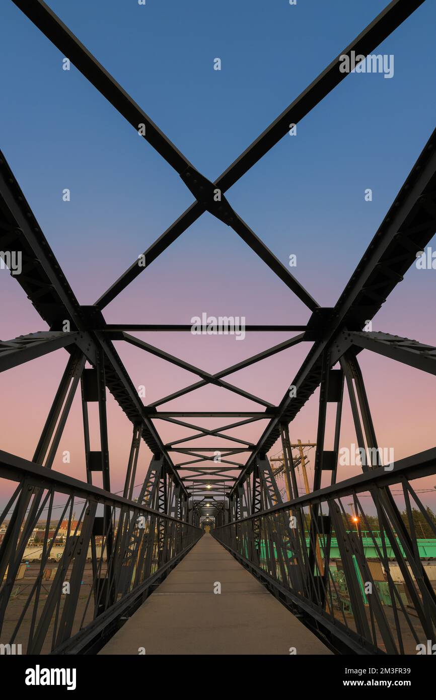 Downtown pedestrian footbridge over railroad tracks at sunset in ...