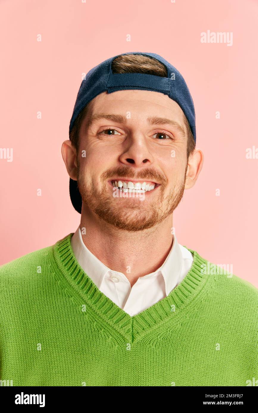 Portrait of young man in cap posing, smiling isolated over pink ...