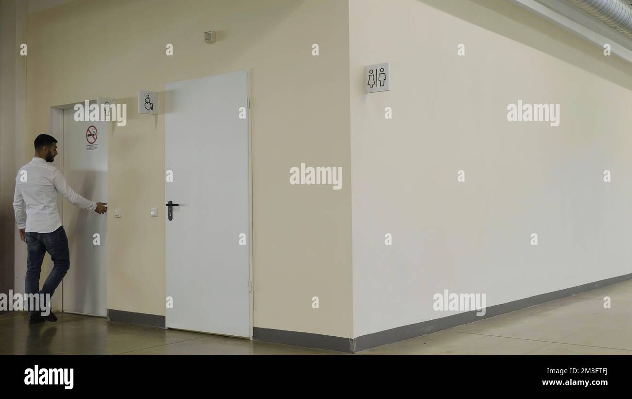 Young man walking inside the public bathroom inside shopping mall. HDR ...