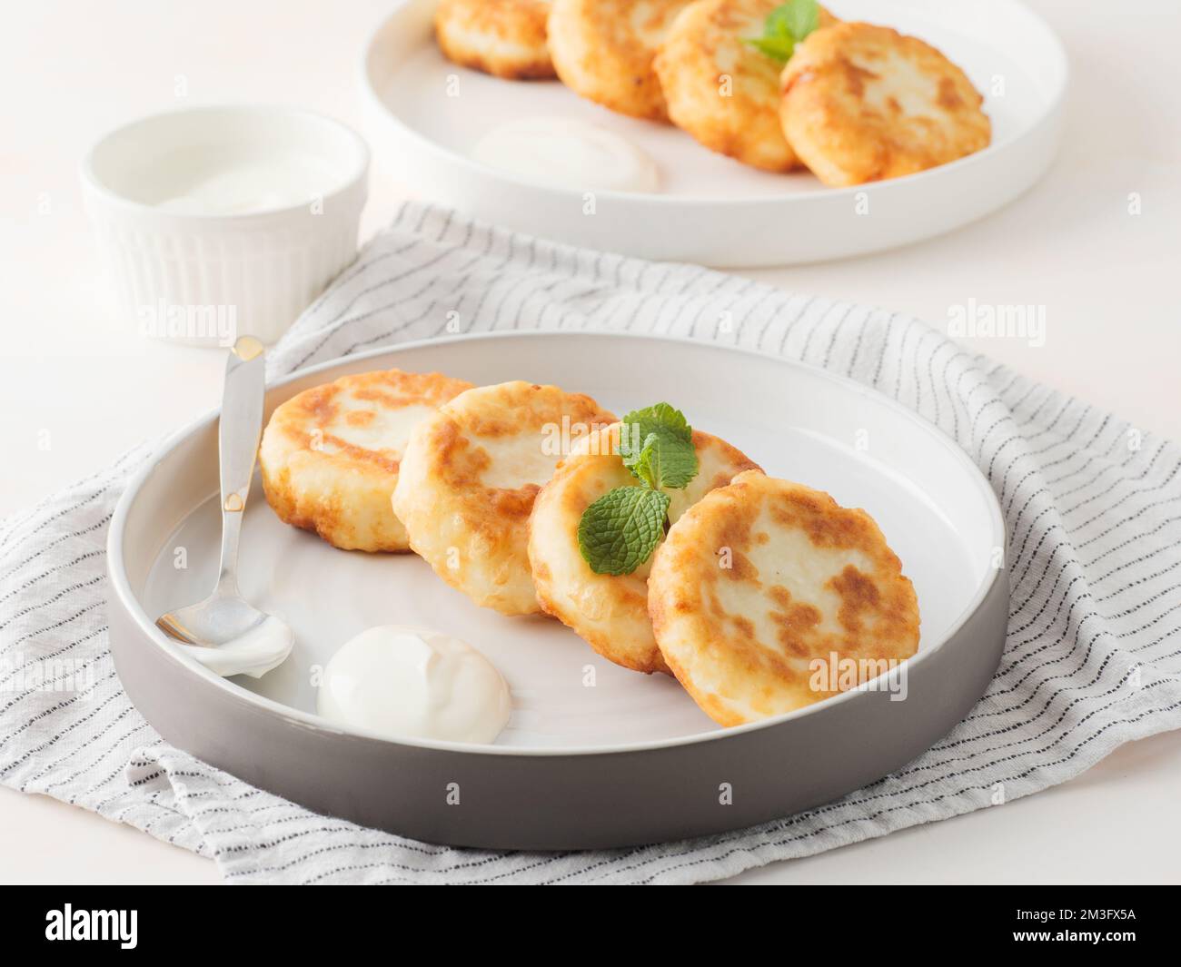 Cottage cheese pancakes, syrniki, on a light background. Copy space ...