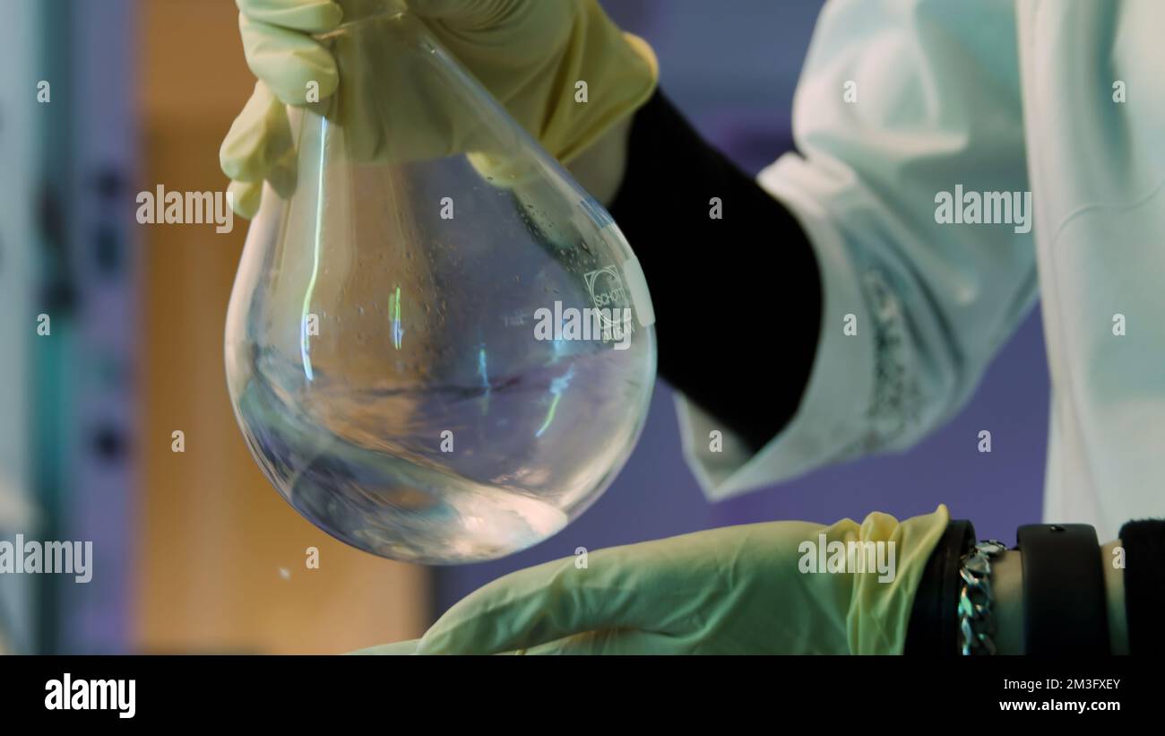 Laboratory researcher experimenting with liquid substance inside flask ...