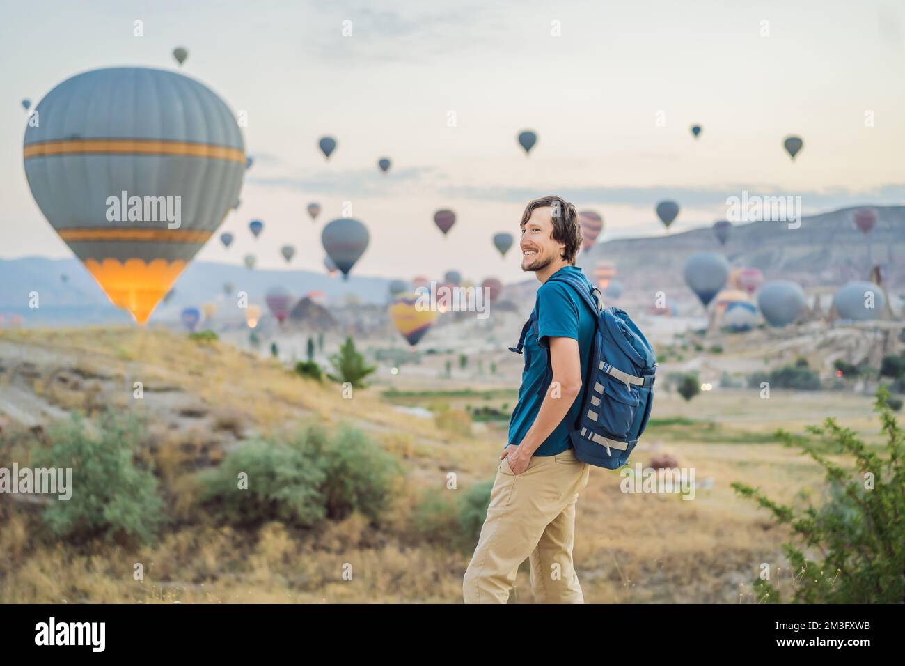 Tourist man looking at hot air balloons in Cappadocia, Turkey. Happy ...