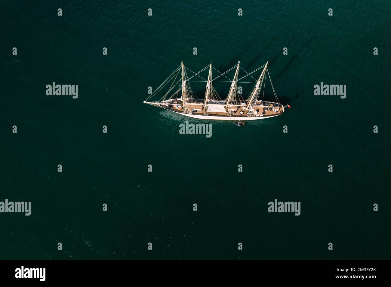 An aerial view of a white ship without sails on the green seawater ...