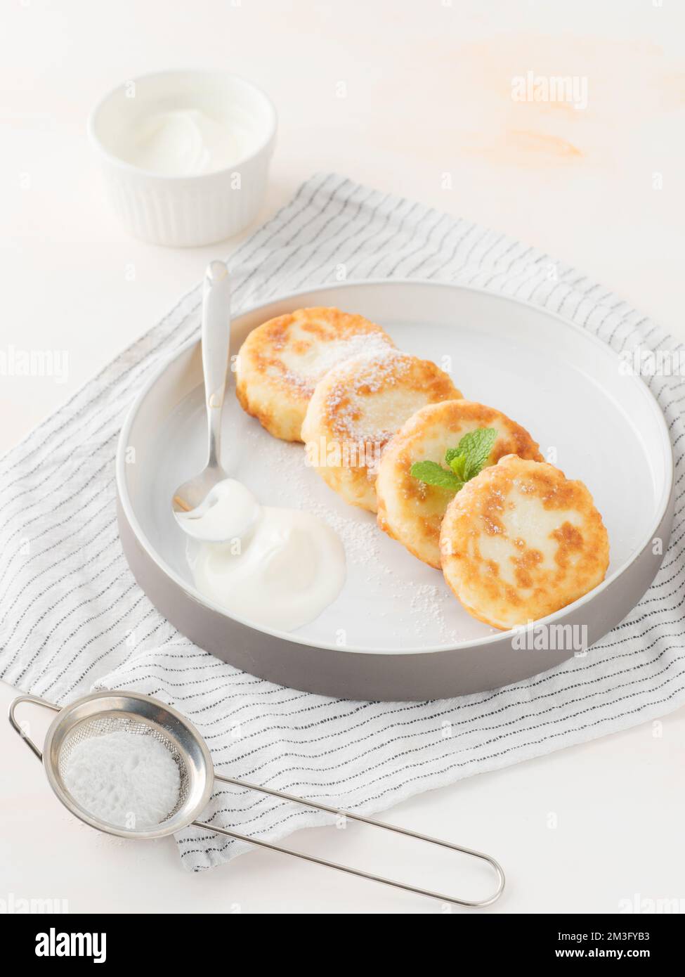 Cottage cheese pancakes, syrniki, on a light background. Copy space ...