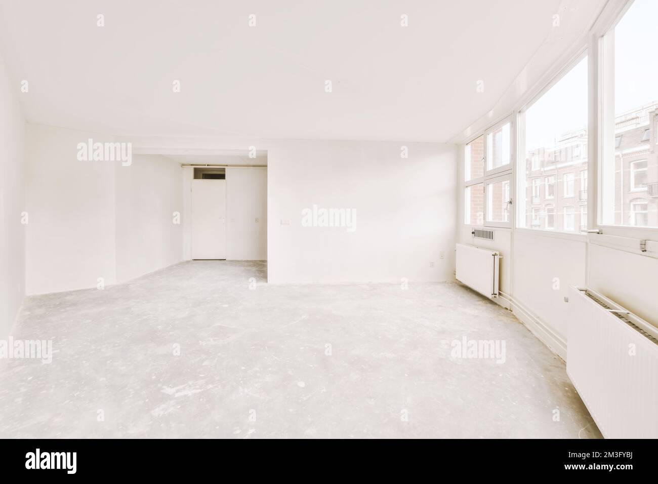 an empty room with white walls and floor to the right, there is a rad door in the corner Stock ...