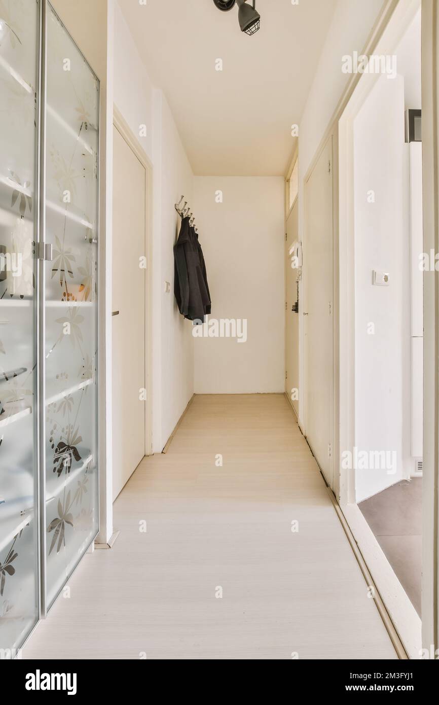a long hallway with white walls and wood flooring on the right side ...
