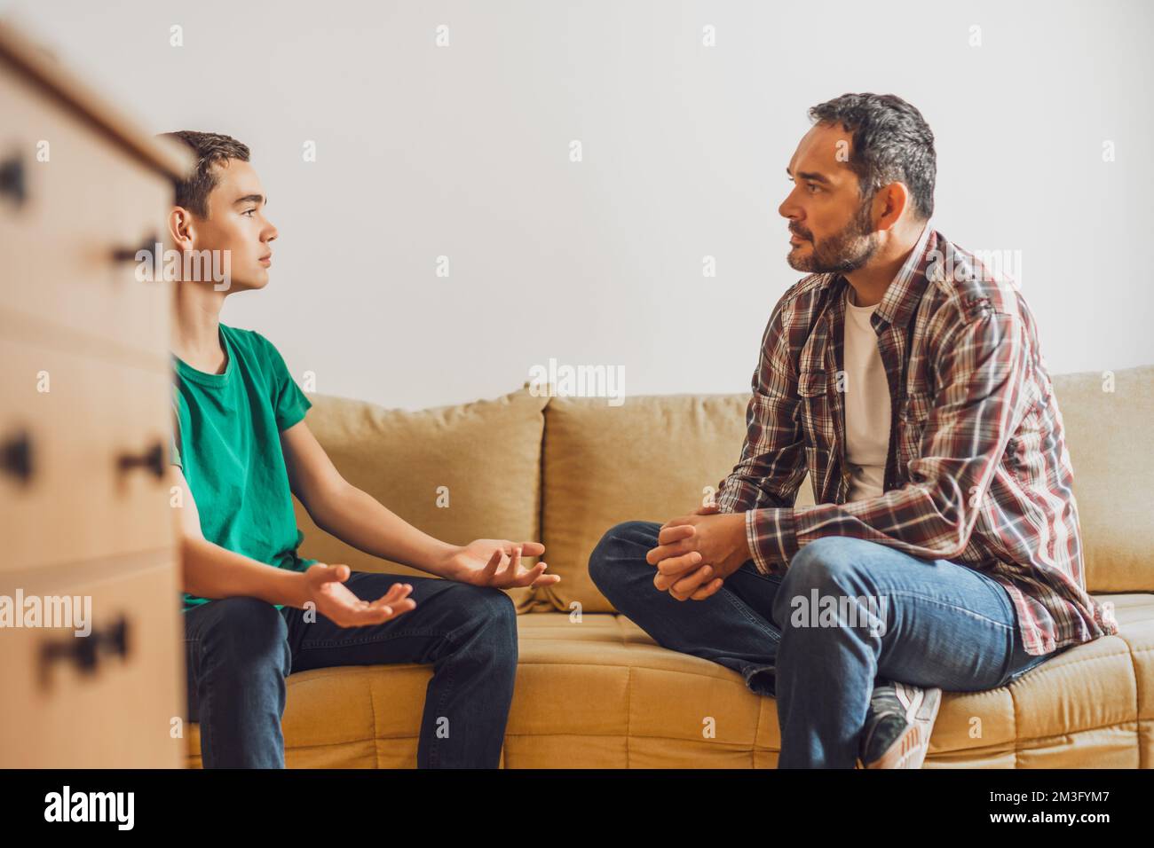 Father and son are talking at home. Son is having issues and father is ...