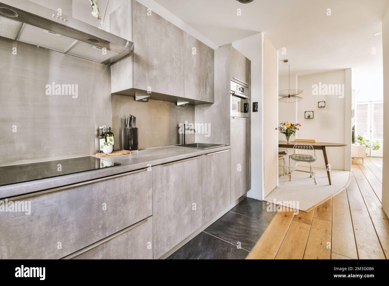 a modern kitchen with wood flooring and stainless steel appliances on ...