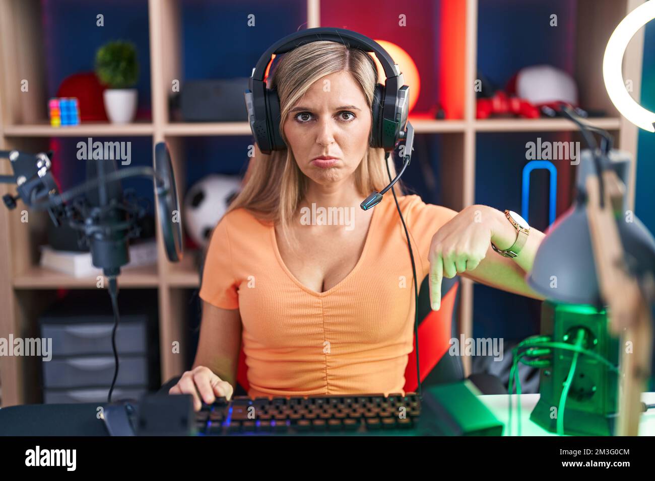 Young woman playing video games pointing down looking sad and upset ...