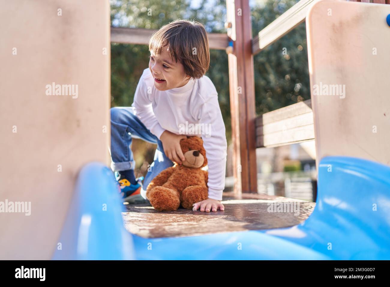 Down syndrome kid smiling confident playing with teddy bear on slide at park Stock Photo - Alamy