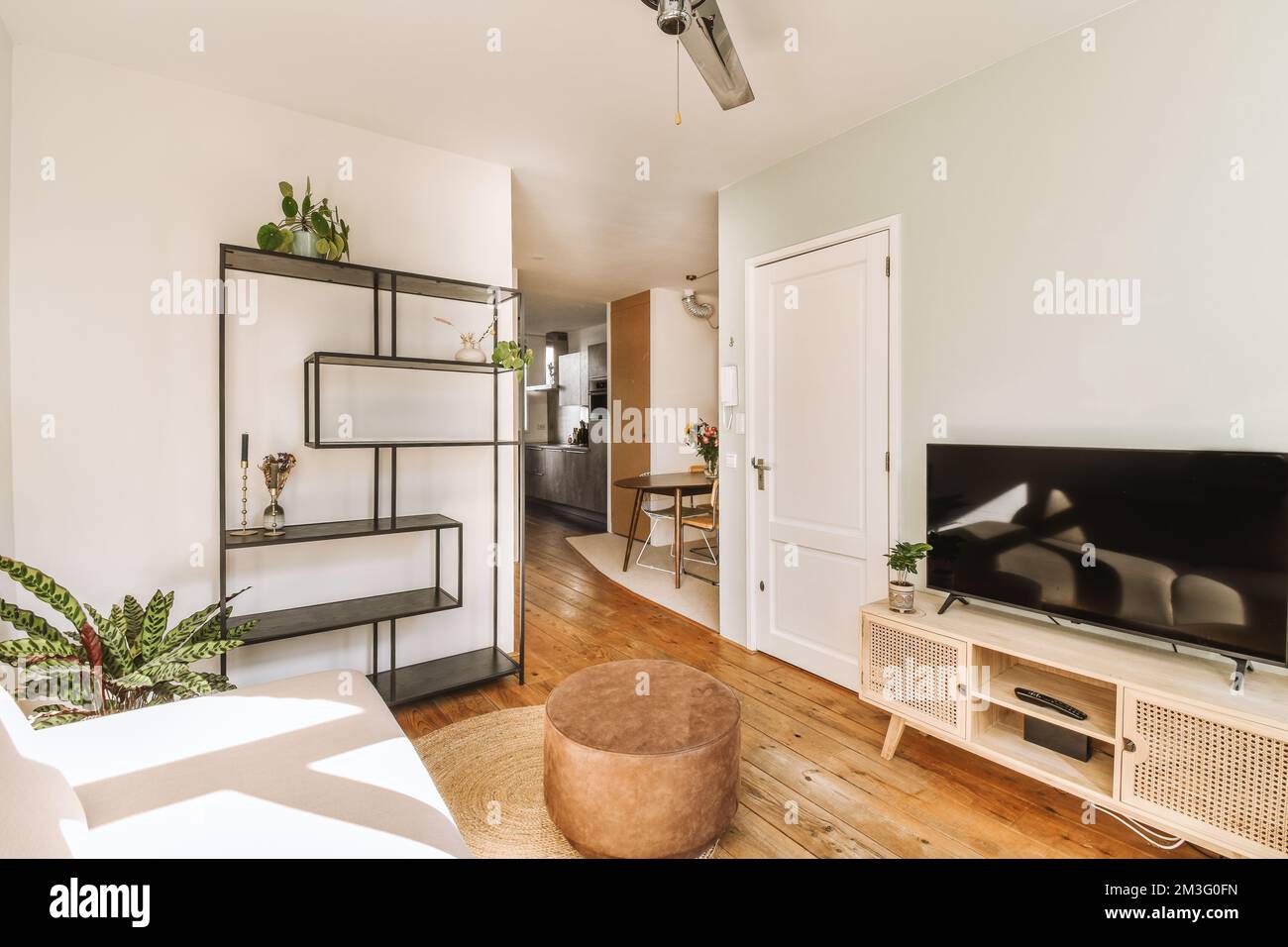 a living room with white walls and wood flooring, there is a large flat ...