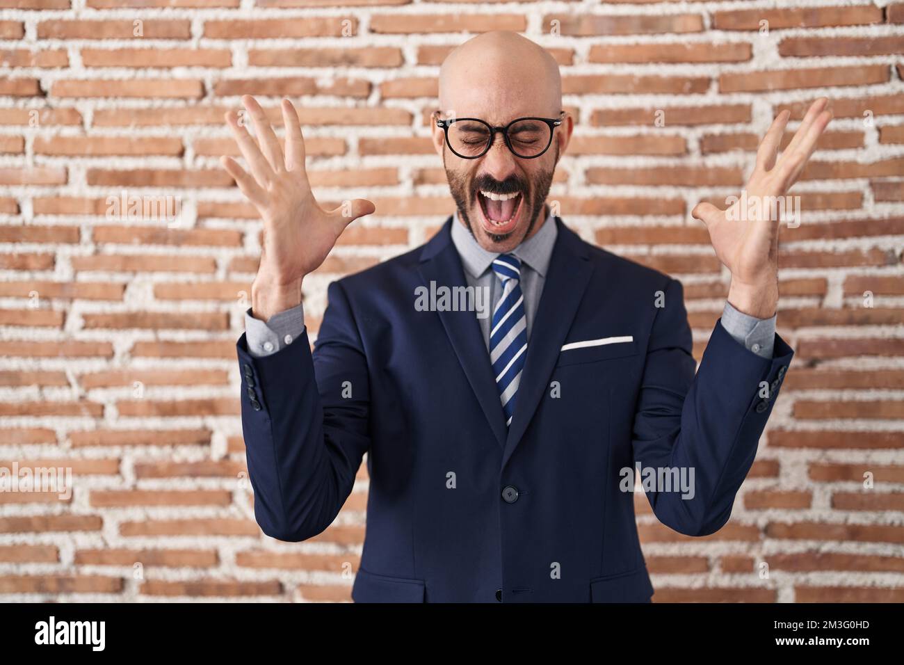 Bald man with beard wearing business clothes and glasses celebrating ...