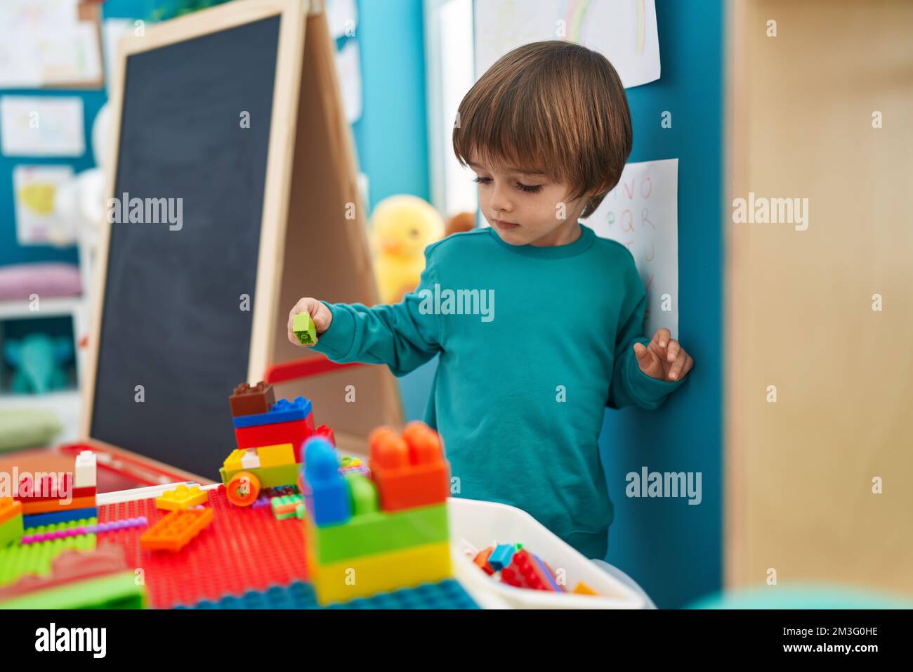 Adorable toddler playing with construction blocks standing at ...