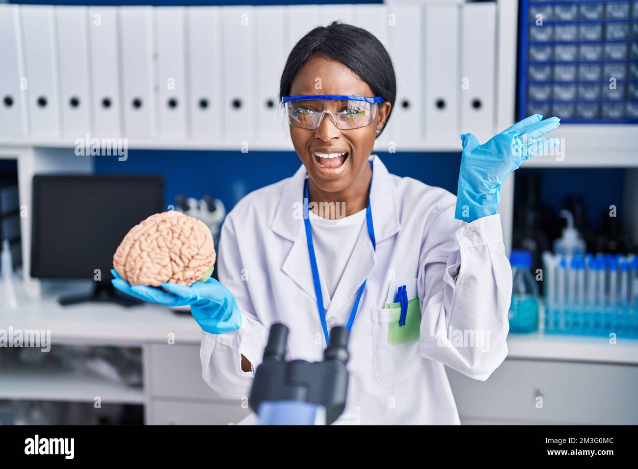 African young woman working at scientist laboratory holding brain ...