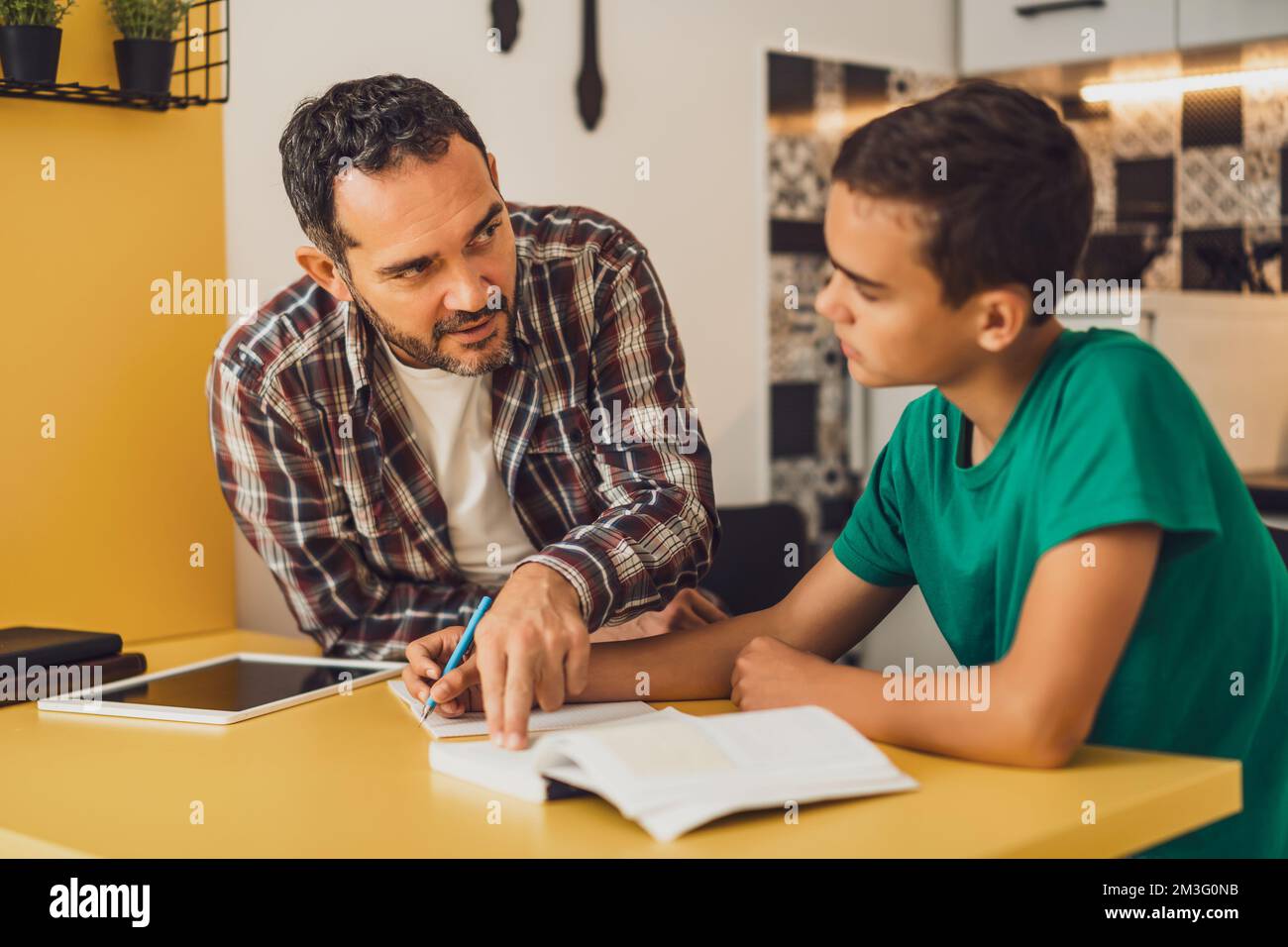 Father is helping his son with learning. They are doing homework ...
