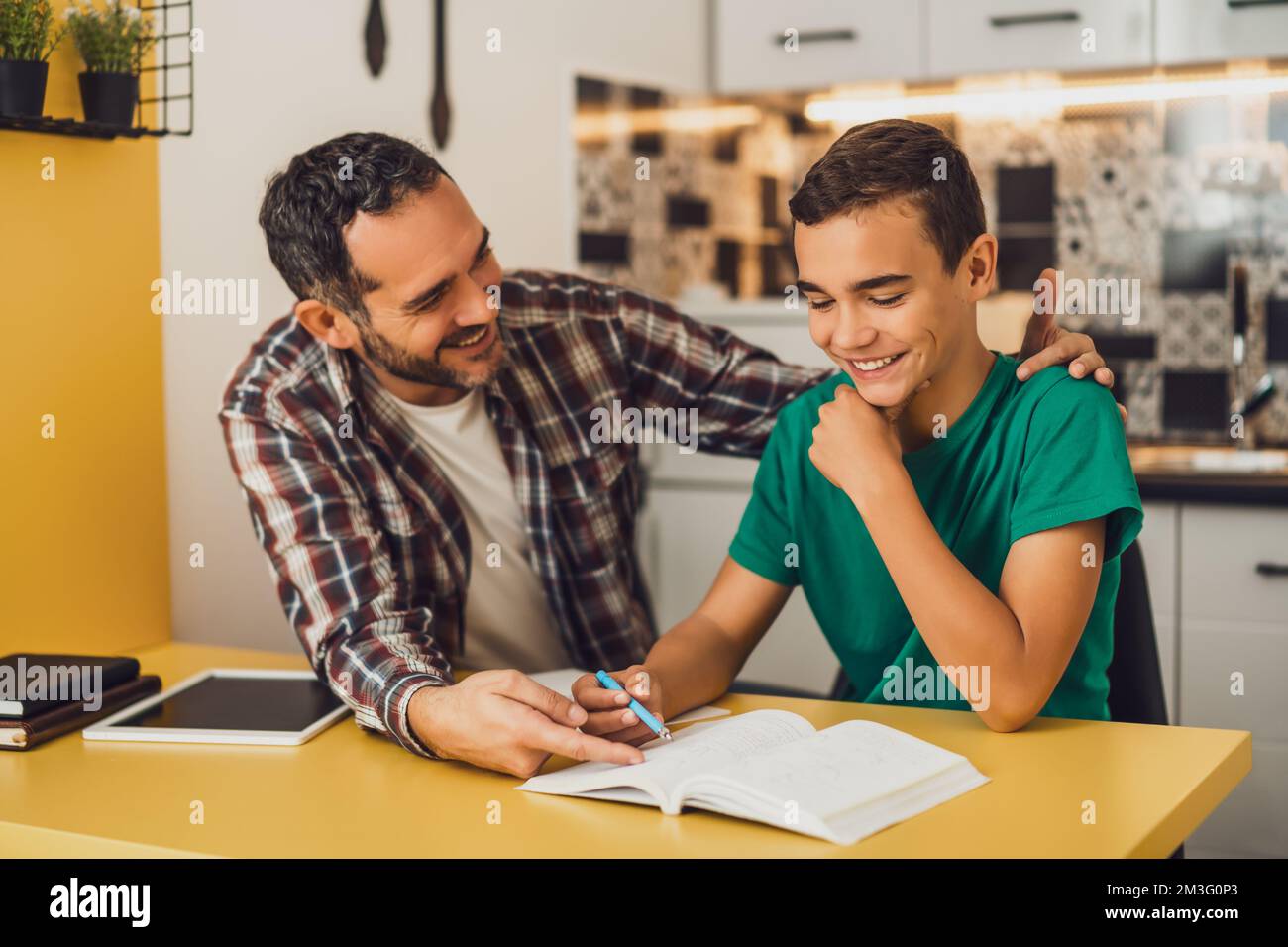 Father is helping his son with learning. They are doing homework ...