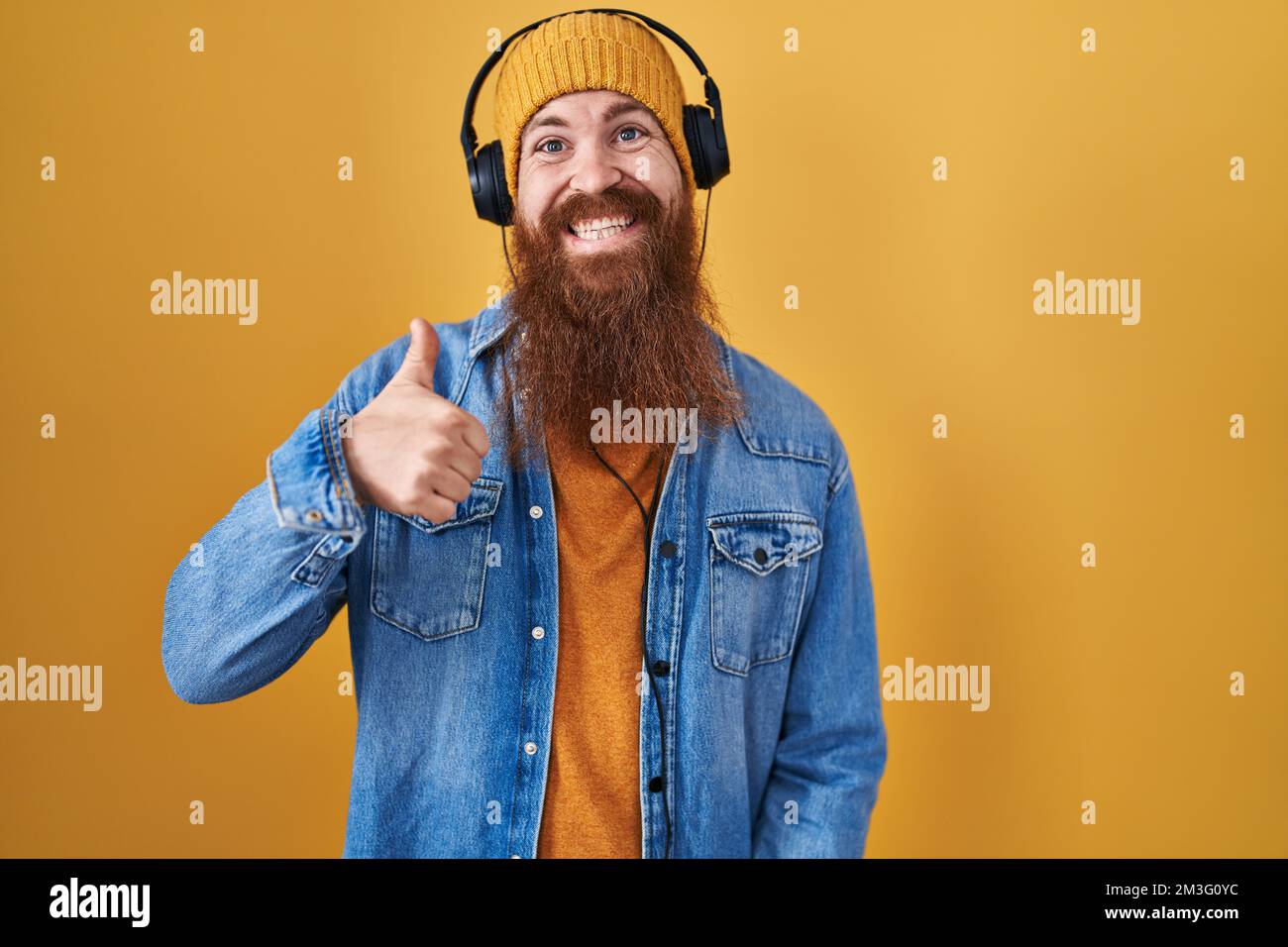 Caucasian man with long beard listening to music using headphones doing ...