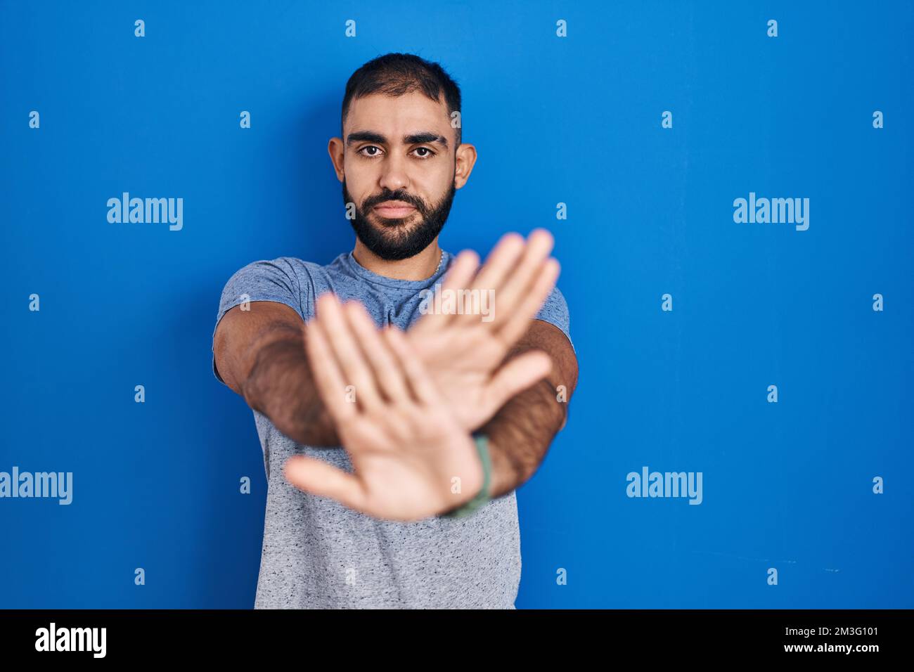 Middle east man with beard standing over blue background rejection ...