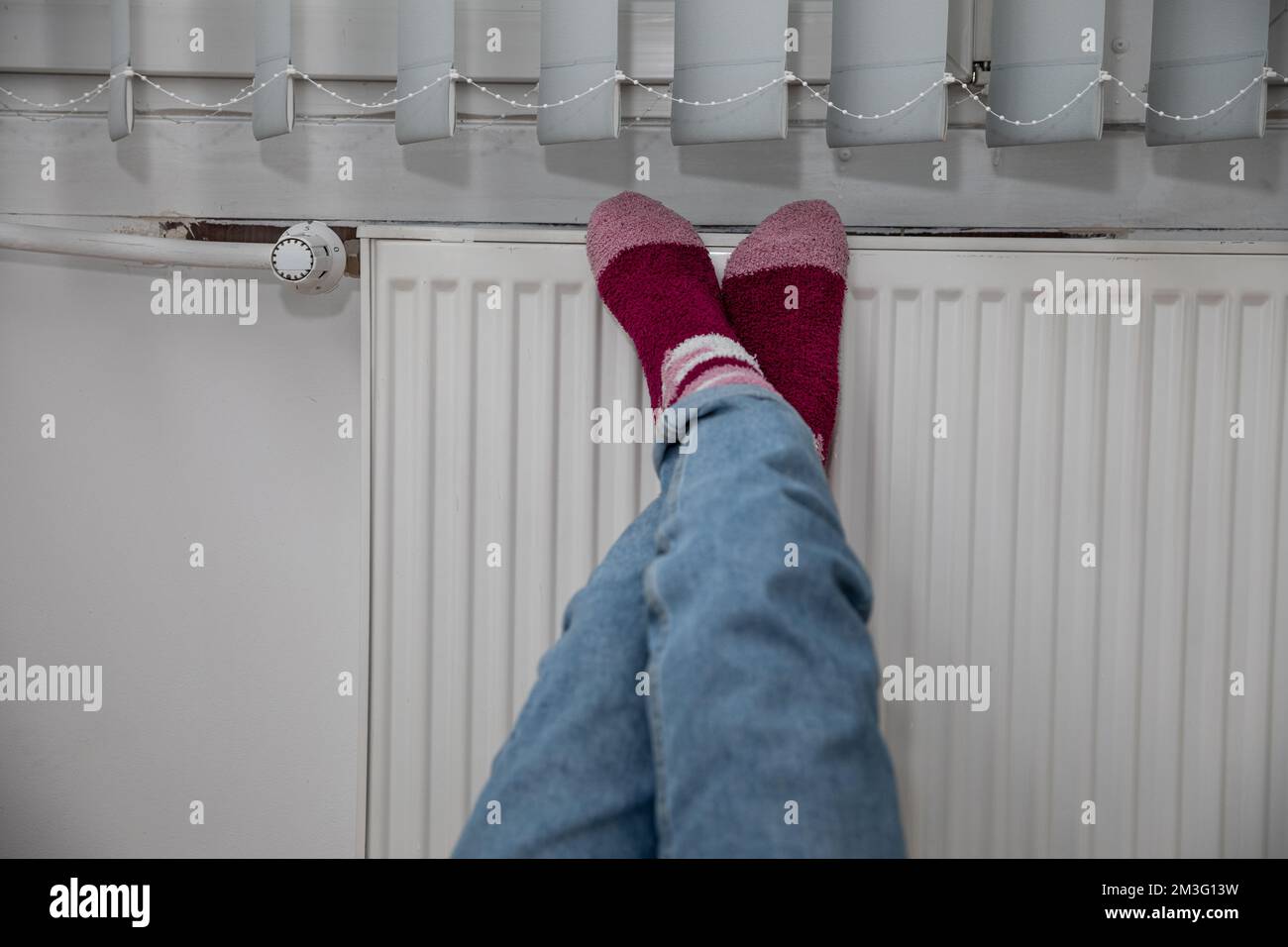 Warming cold feet on a hot radiator. Thick wool socks Stock Photo - Alamy